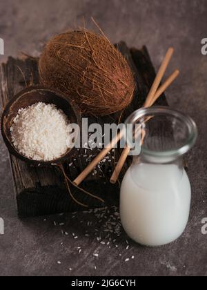Bottle of coconut vegan milk with straws, whole coconut and flakes ...