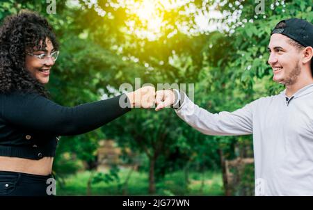 Two teenage friends bumping their fists. A guy and teenage girl shaking ...