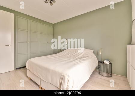 Comfortable bed located near balcony door with curtains in cozy light ...