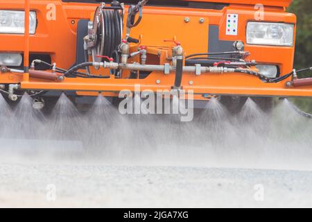 Big orange machine clears the asphalt with a sweeper near the curb ...