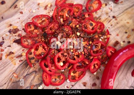Fresh red chili peppers round slices on wooden cutting board at ...