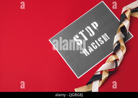 Braided ribbons and paper sheet with text STOP RACISM on color ...