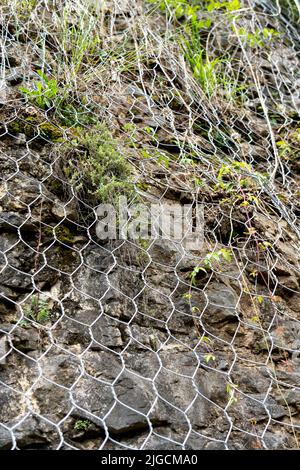 Natural rock with mesh to protect against landslides dangerously ...