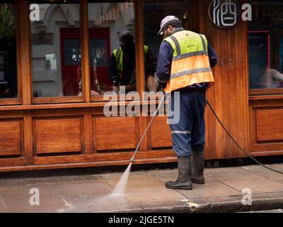 Veolia street cleaner, cleaning pavement in Soho London, with pressure ...