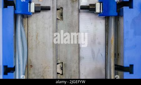 Close-up injection molding machine making blue forms. Moving back and ...
