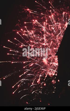 A vertical shot of exploding red fireworks in the sky at night Stock ...