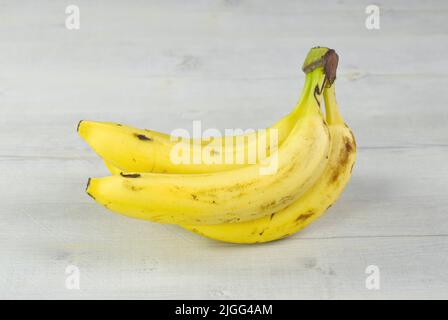 Banana bunch on a light wooden background Stock Photo - Alamy