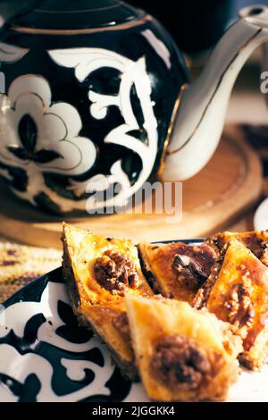 Cup of Turkish tea, sweets and teapot on wooden table against white ...