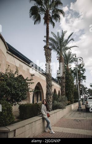 Woman stand near old building with columns and tropical plants in ...