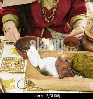 A woman in ancient Byzantine clothing makes yarn and sews from vintage ...