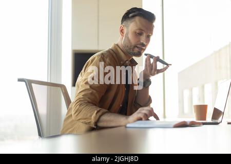 Male Entrepreneur Using Voice Search On Phone Sitting In Office Stock ...