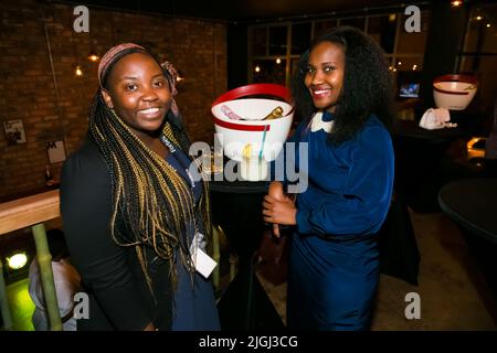 Two African women guests socializing in a sushi restaurant in ...