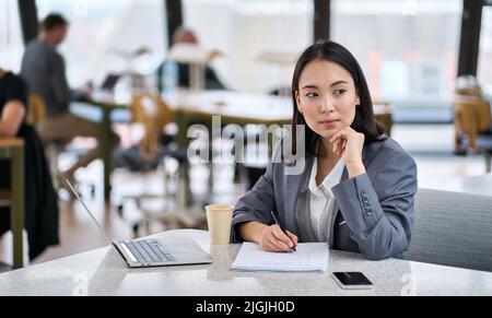Young Asian woman professional thinking contemplating while writing ...