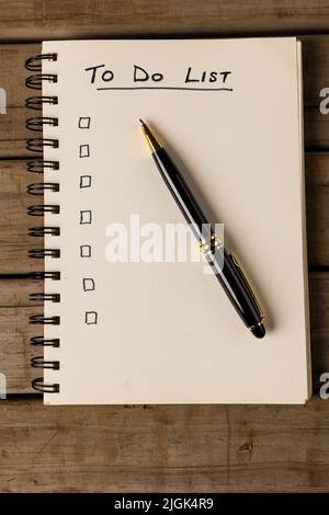 Vertical image of notebook with to do list and copy space on wooden ...