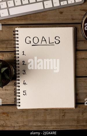 Vertical image of notebook with goals and copy space on wooden surface ...