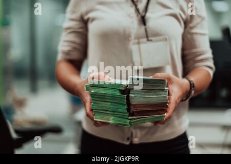 Bank employees holding a pile of paper banknotes while sorting and ...