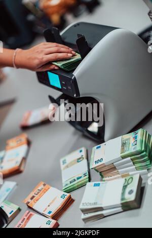 Bank employees using money counting machine while sorting and counting ...