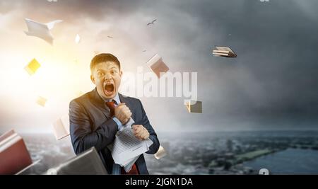 Young stressed man ripping documents with frustrated facial expression ...