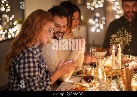 friends with cellphone having dinner party at home Stock Photo - Alamy