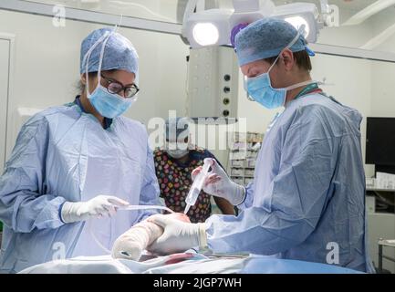 Two surgeons perform an operation on the arm of a patient in an NHS ...