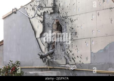 An unexploded rocket is seen in the wall of a house located in a ...