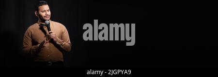 skeptical indian comedian in shirt and bow tie holding microphone ...