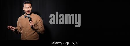 indian stand up comedian with bow tie holding microphone during ...