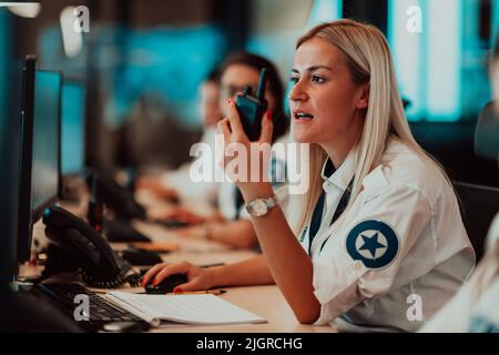 Female security operator holding portable radio in hand while working ...