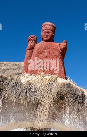 A very old carved stone statue of a bishop over the entry arch to the ...