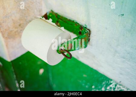 A roll of the cheapest single ply toilet paper on a toilet paper holder ...