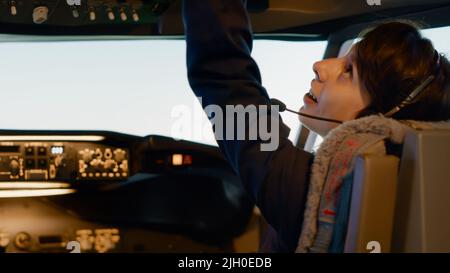Female copilot pushing buttons and switch on dashboard panel, flying ...