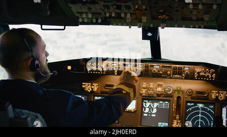 Pilot aviator fixing altitude and longitude level on dashboard in plane ...