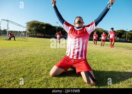 Male soccer player kneeling with arm raised Stock Photo - Alamy