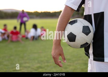 Midsection of caucasian male player in red jersey holding soccer ball ...