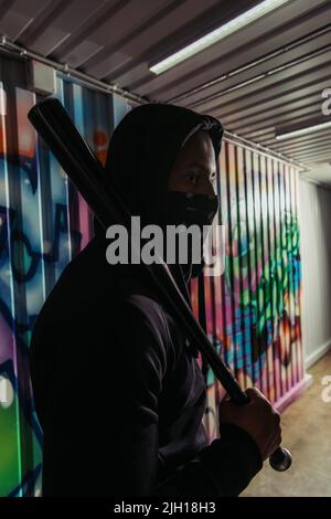 African american hooligan in mask on face and glove holding baseball ...