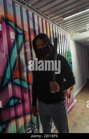 African american vandal with scarf on face drawing graffiti on wall ...