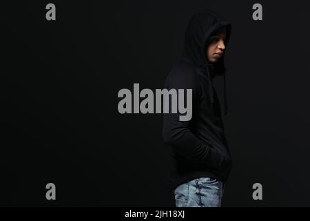 African american hooligan in hoodie standing isolated on black Stock ...