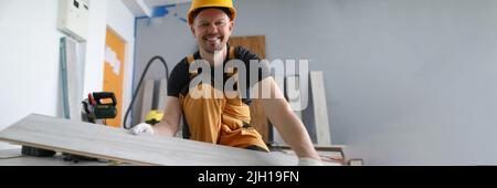 Qualified carpenter smile and put wooden plank on floor Stock Photo - Alamy