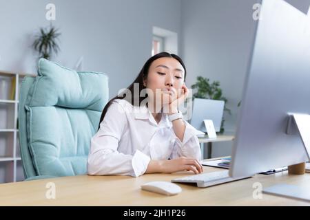 Sad woman sits at her work desk in office over charts with business ...