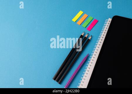 Image of various office supplies, pens and notebook on blue background ...