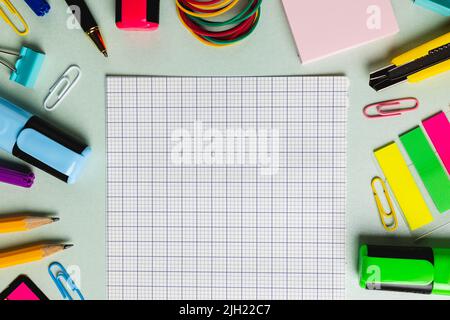 Composition of checked sheet and frame made of school tools on green ...