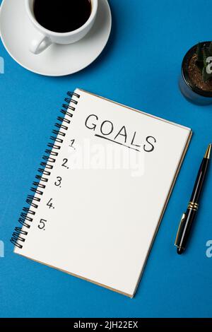Vertical image of notebook with goals and copy space on wooden surface ...