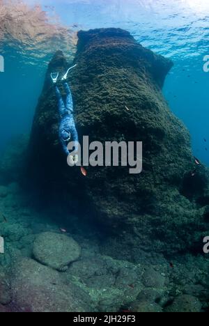 Freediver diving close to a big rock Stock Photo - Alamy