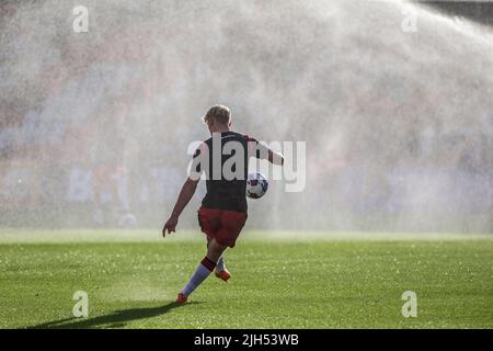 Football warming before a game at lower league match whilst sprinklers ...