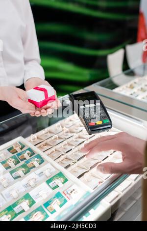 Cropped view of seller holding gift near customer paying with credit ...