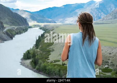 Woman traveler hipster looking forward at amazing mountains and valley ...