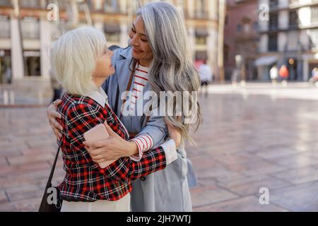 Enthusiastic women spending time together in city Stock Photo - Alamy