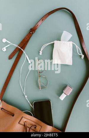 The contents of woman's purse spilling against the pink background ...
