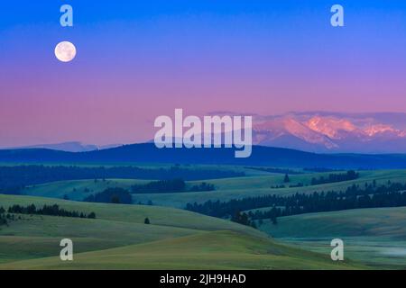 full moon setting at first light over the bridger mountains near ...