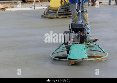 Laborer performing polishing cement screed foundation on the ...